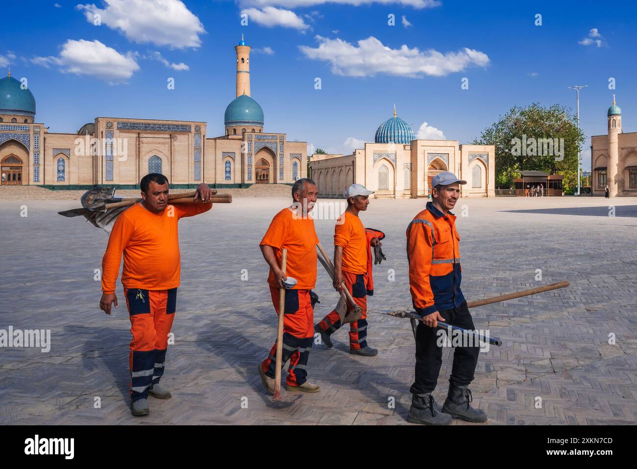 group of Uzbek male janitors in orange uniforms with shovels on the ...