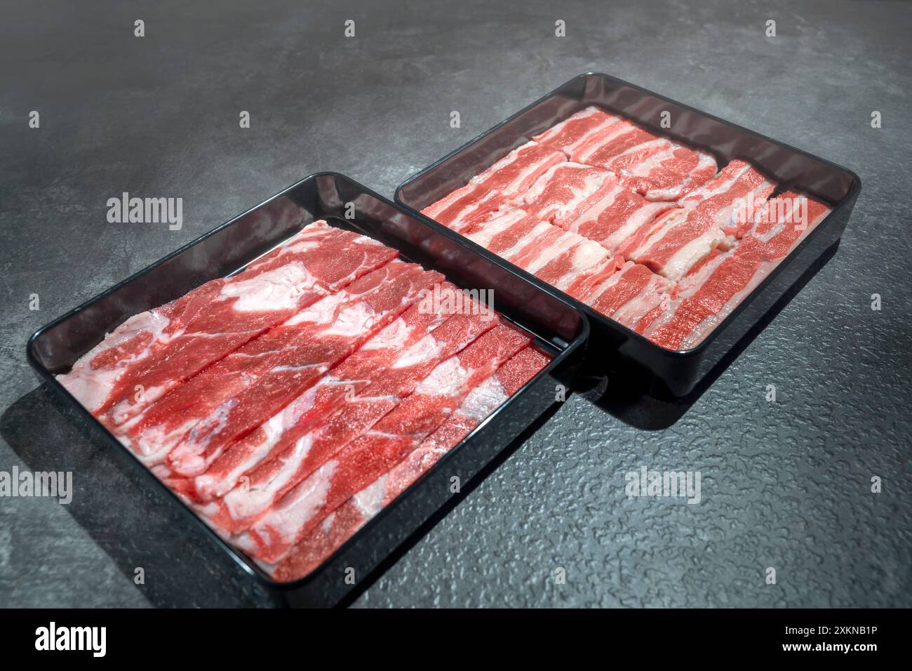 A tray of meat is on a grey surface. The meat is sliced and arranged in ...