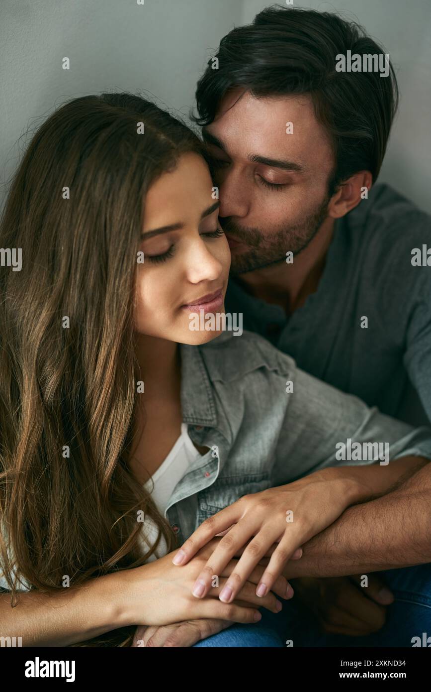Love, hug and couple kiss in home for care, connection or bonding ...