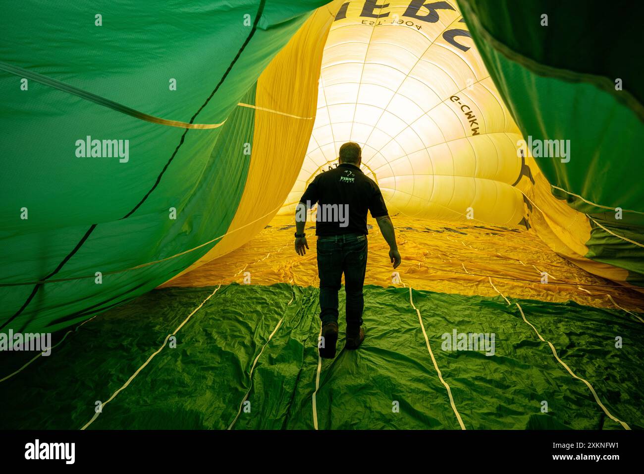 A hot air balloon pilot enters an inflated canopy to check the rigging ...