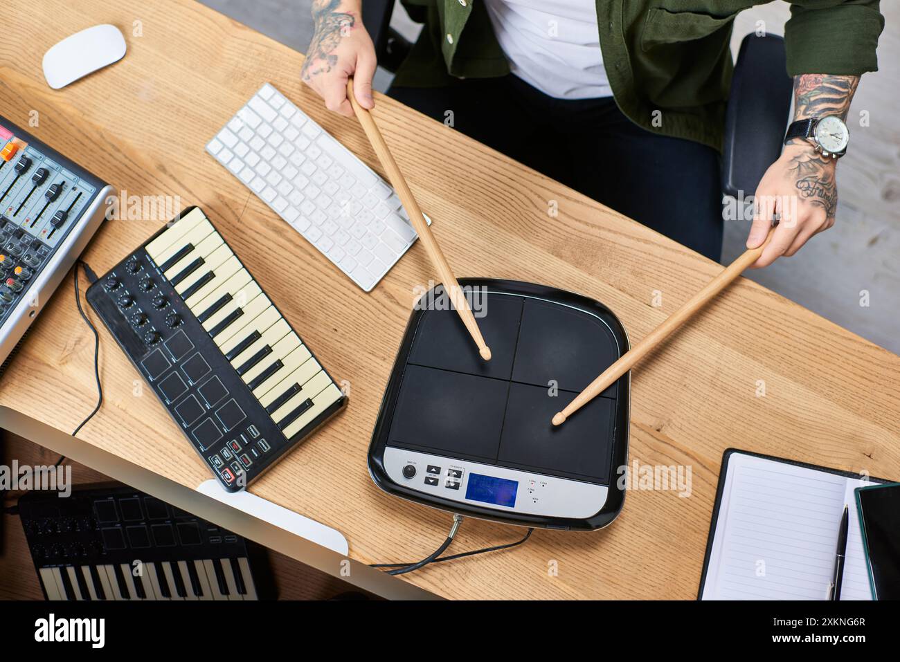 A young Asian man plays a drum pad and keyboard in his studio Stock ...
