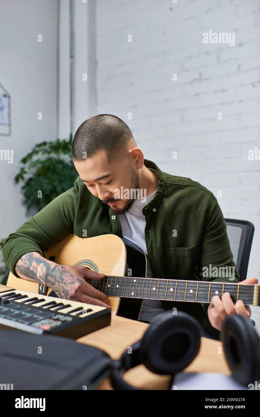 A handsome Asian man, a multi-instrumentalist, plays an acoustic guitar ...