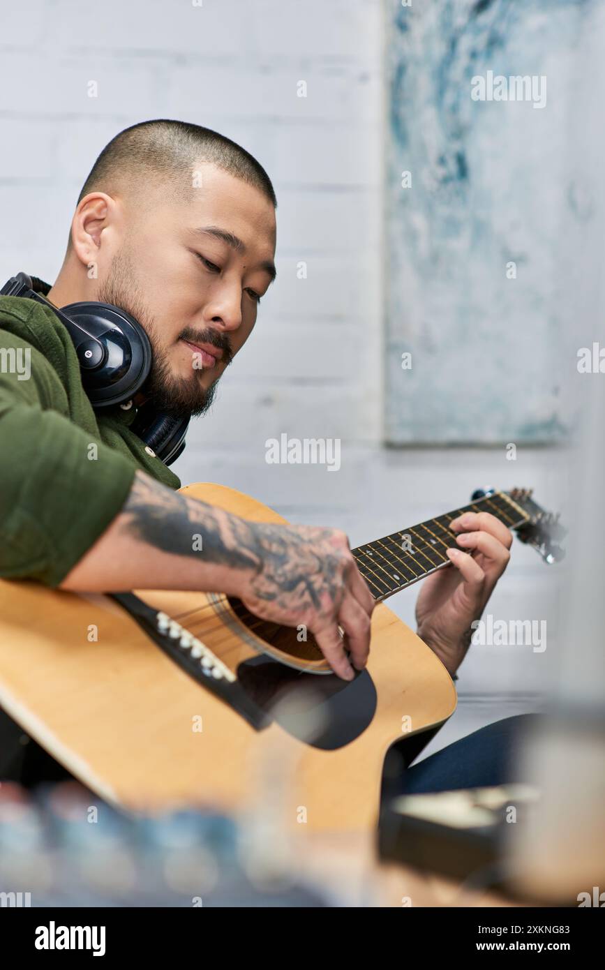 A talented Asian musician plays an acoustic guitar in his studio Stock ...