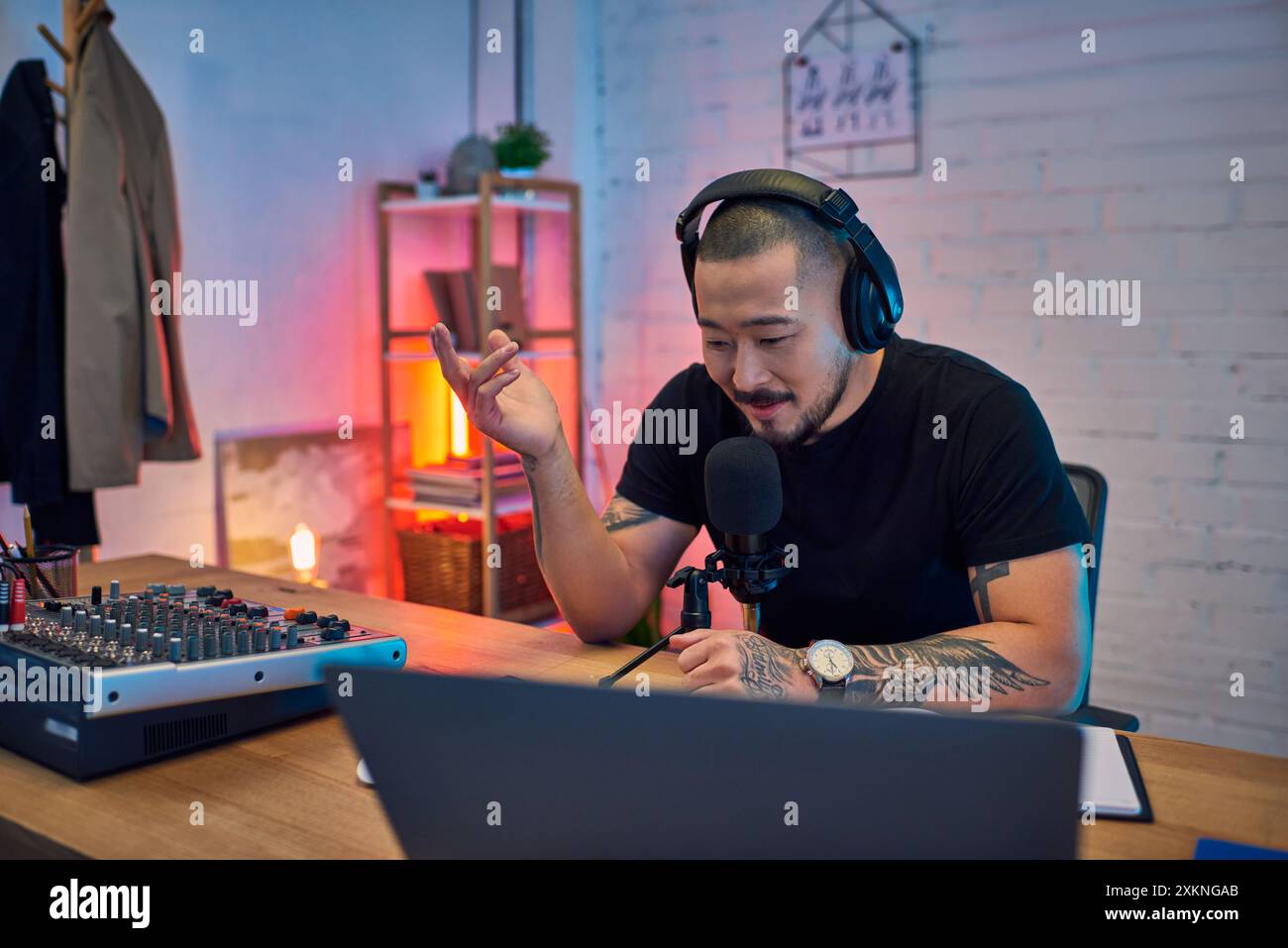 A handsome Asian man records a podcast in his home studio, wearing ...