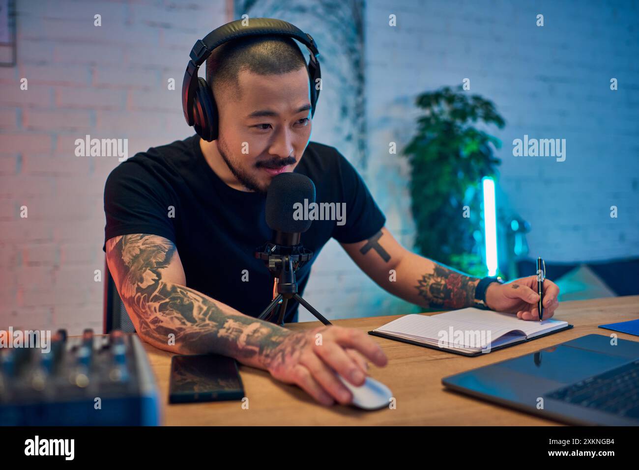 A handsome Asian man podcasts in his home studio, wearing headphones ...