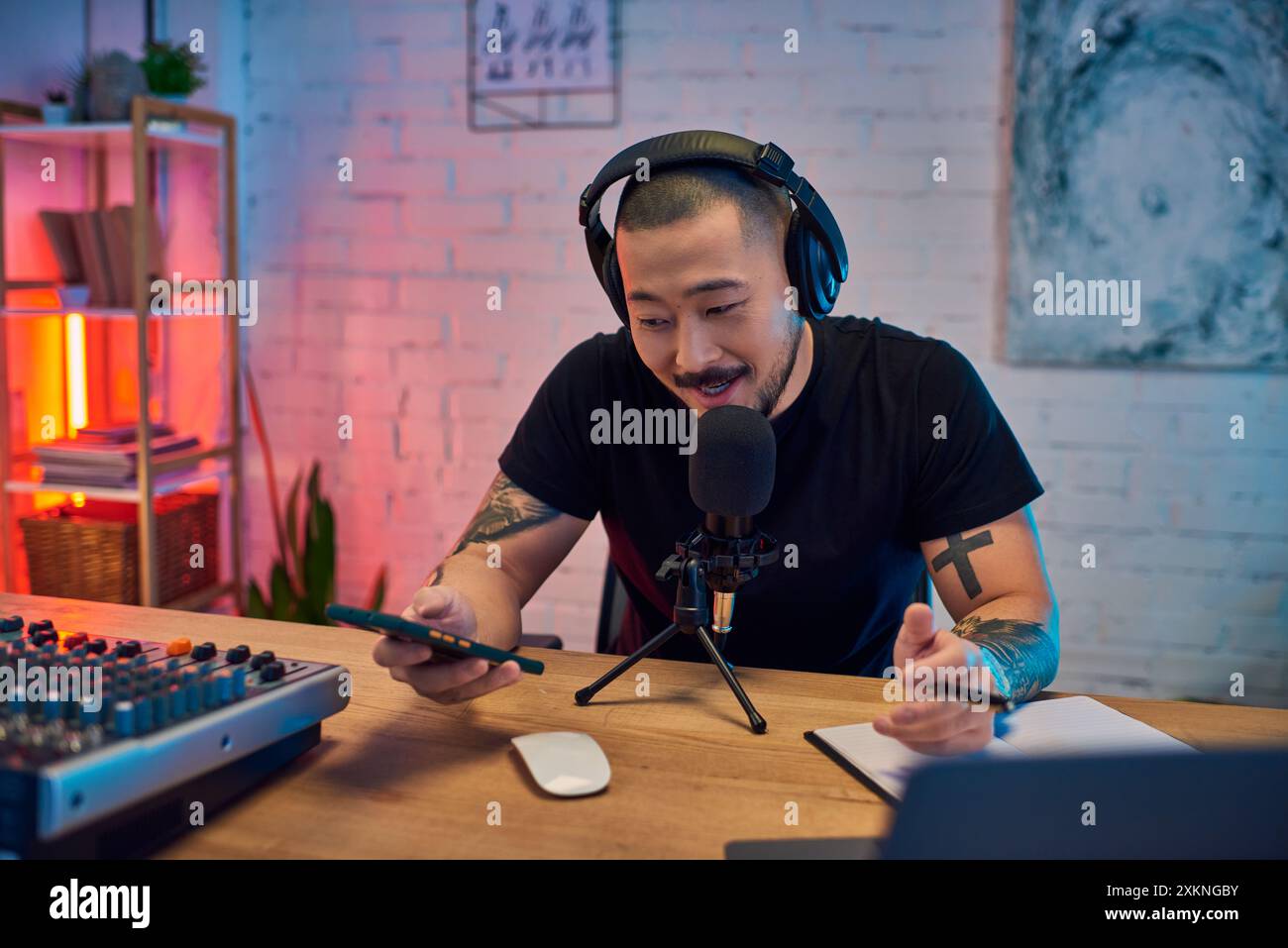 A handsome Asian man is recording a podcast in his home studio, wearing ...