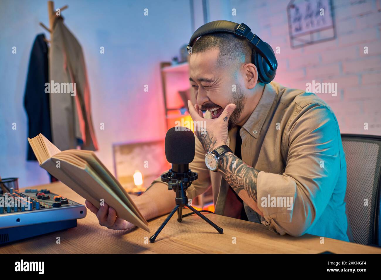 A handsome Asian man laughs while podcasting in his home studio Stock Photo - Alamy
