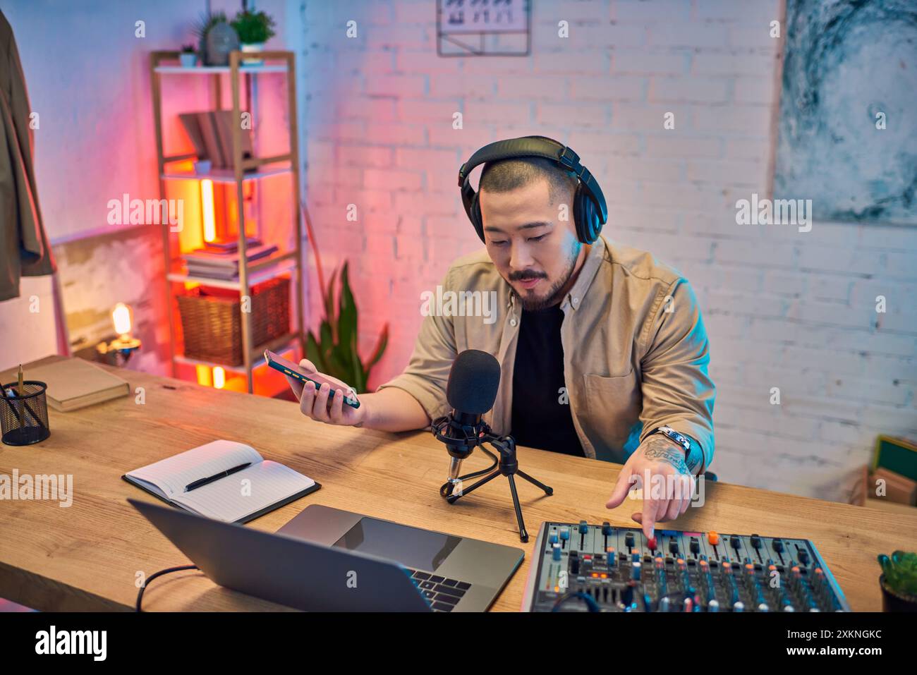 A handsome Asian man records a podcast in his home studio, adjusting ...