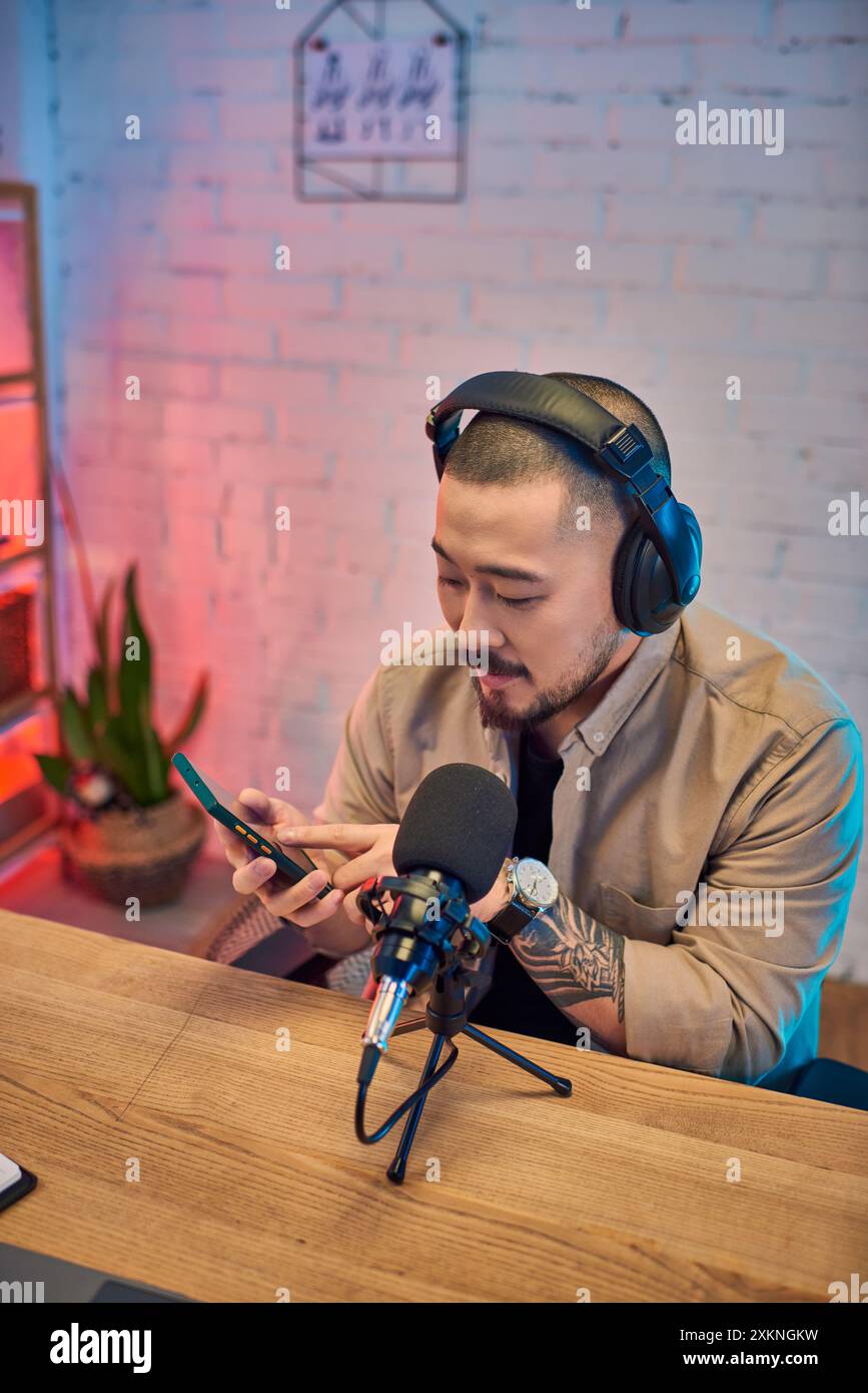 A handsome Asian man records a podcast in his studio Stock Photo - Alamy