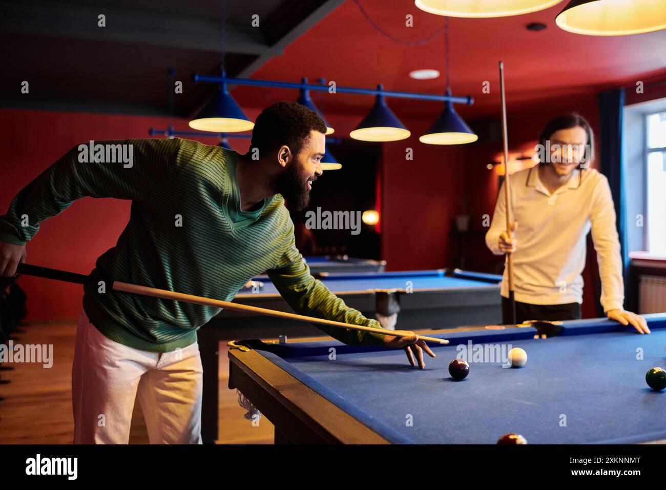 Friends play a casual game of billiards in a dimly lit lounge Stock ...
