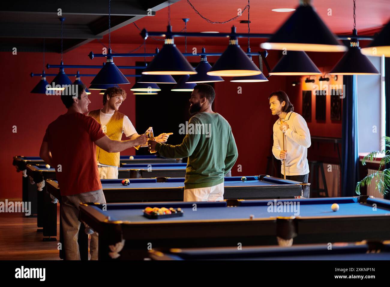 Friends play billiards in a brightly lit room with blue pool tables and ...