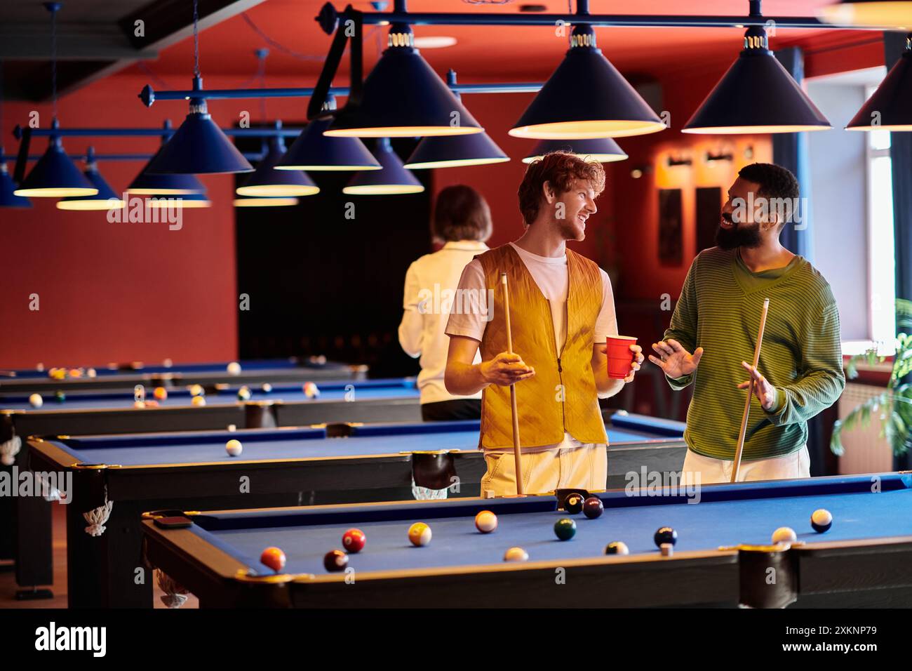 Friends play billiards in a dimly lit pool hall Stock Photo - Alamy
