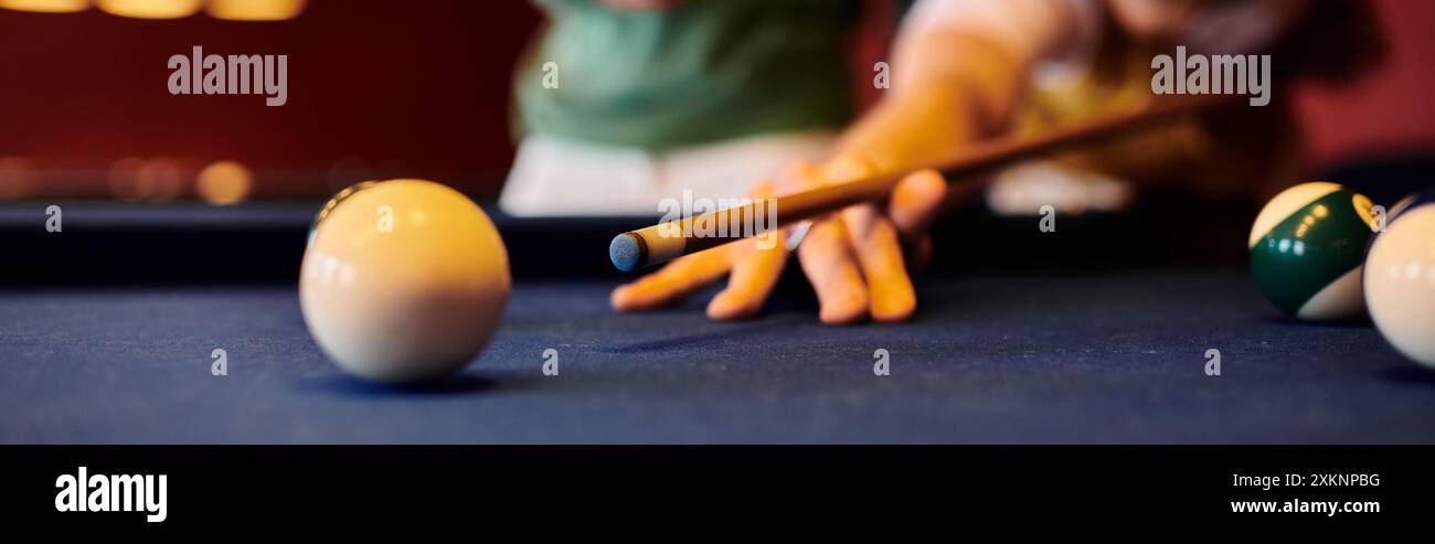 A person taking aim with a pool cue, focusing on the white cue ball ...