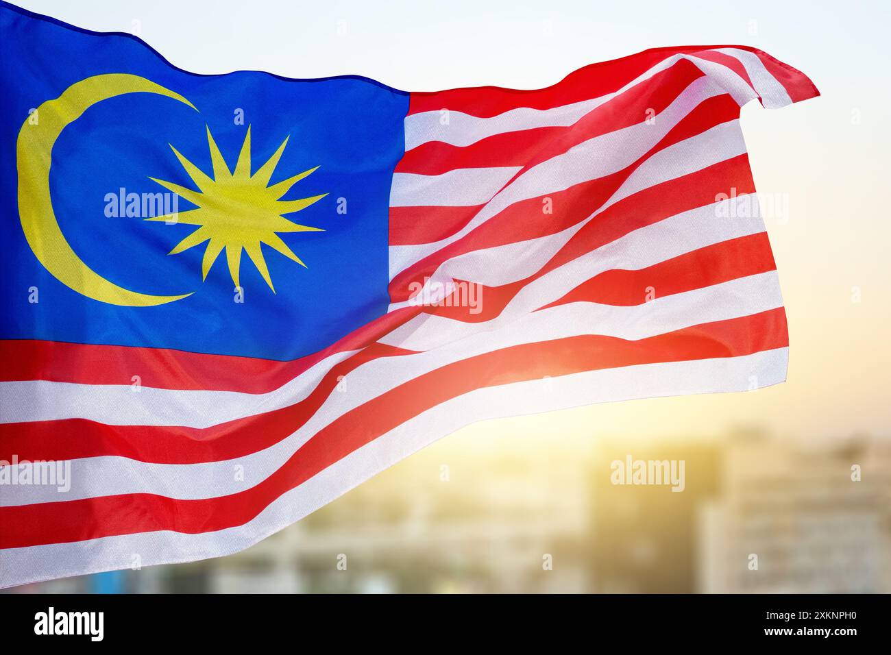 A Malaysia flag with a blue star and red stripes is flying in the air ...