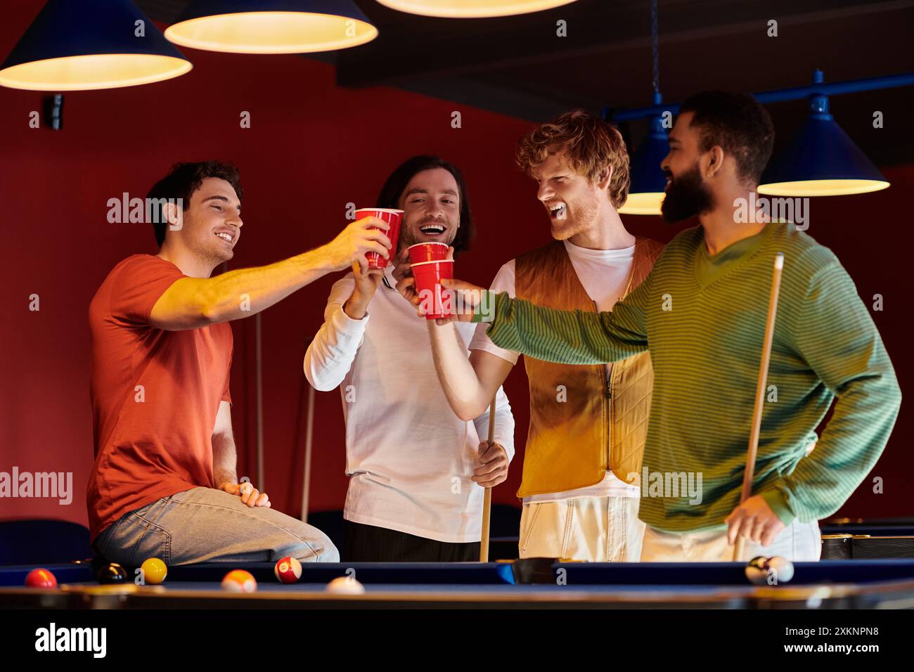 Friends raise their red cups in a toast during a relaxed billiards game ...