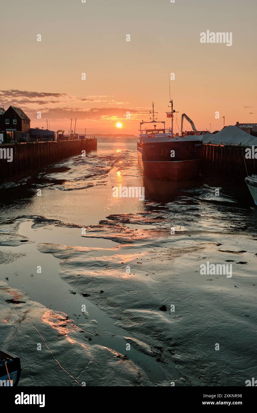 Sunset over Whitstable dock at low tide in Whitstable, Kent showing mud ...