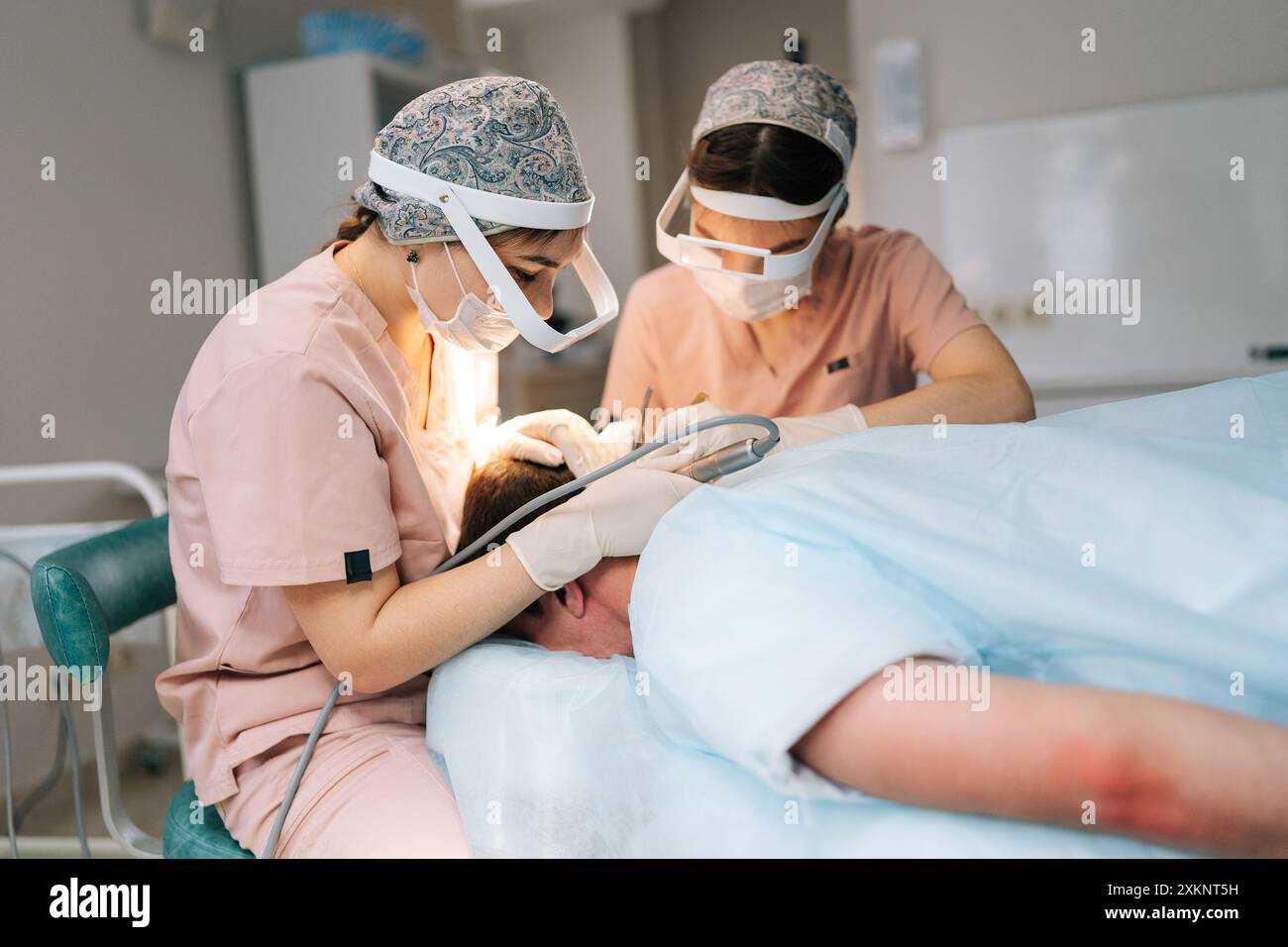 Two female doctors collecting hair follicles from donor area of male ...