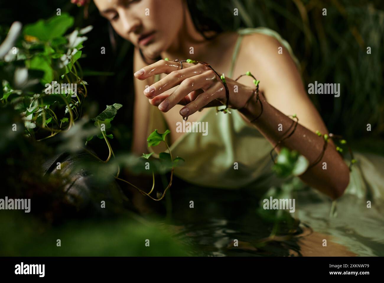 A womans hand emerges from a swamp, adorned with green vines Stock ...