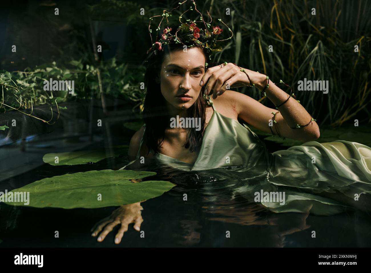 A woman wearing a floral crown and green dress poses in a swamp Stock ...