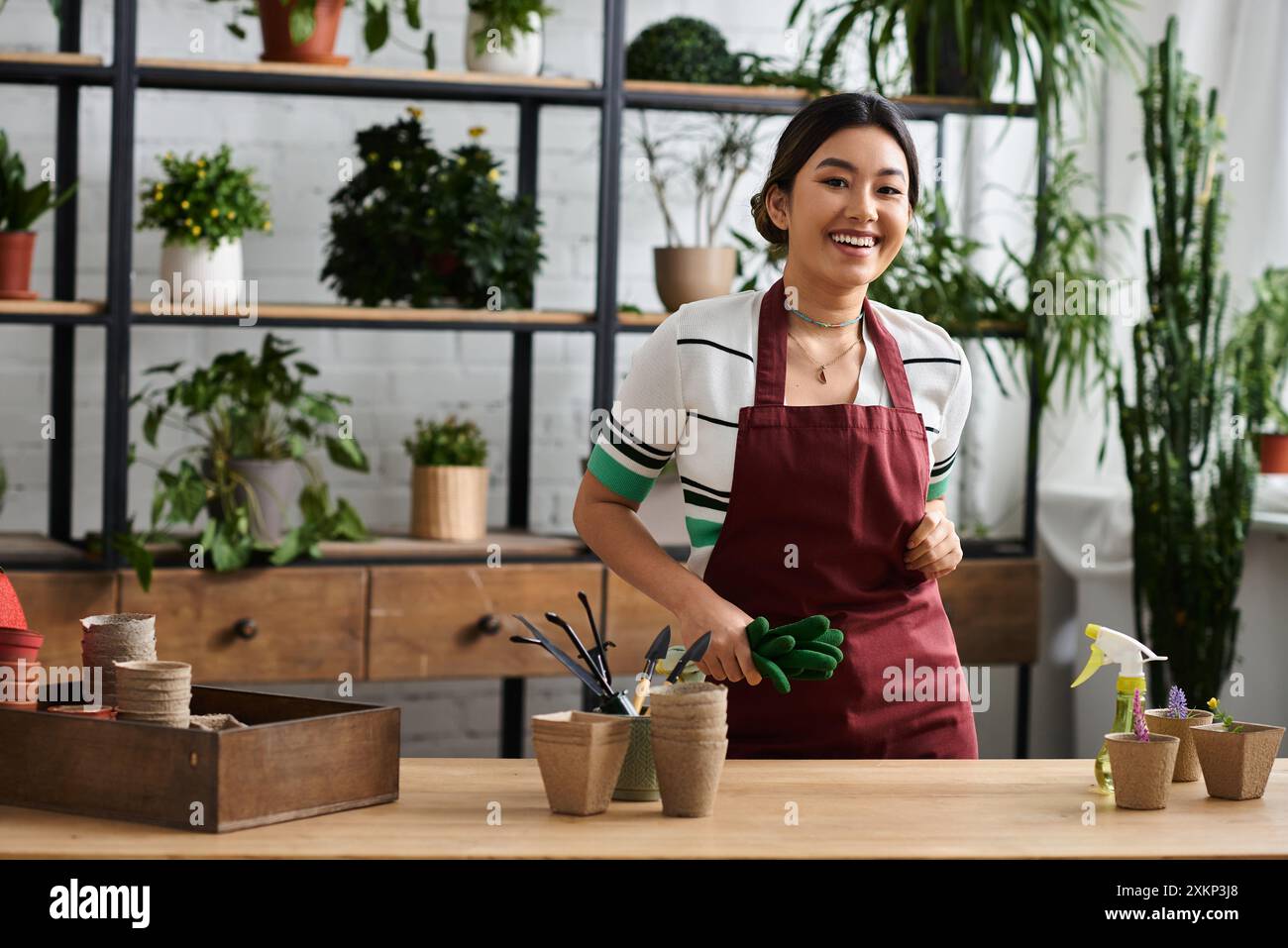 An Asian woman smiles while working at a counter in her plant shop ...