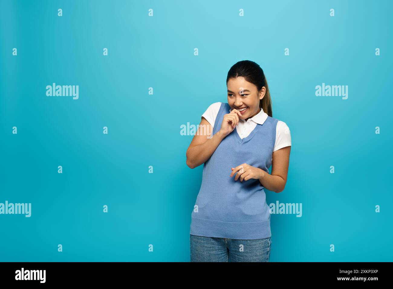 A young Asian woman, wearing smart casual attire, smiles shyly while ...