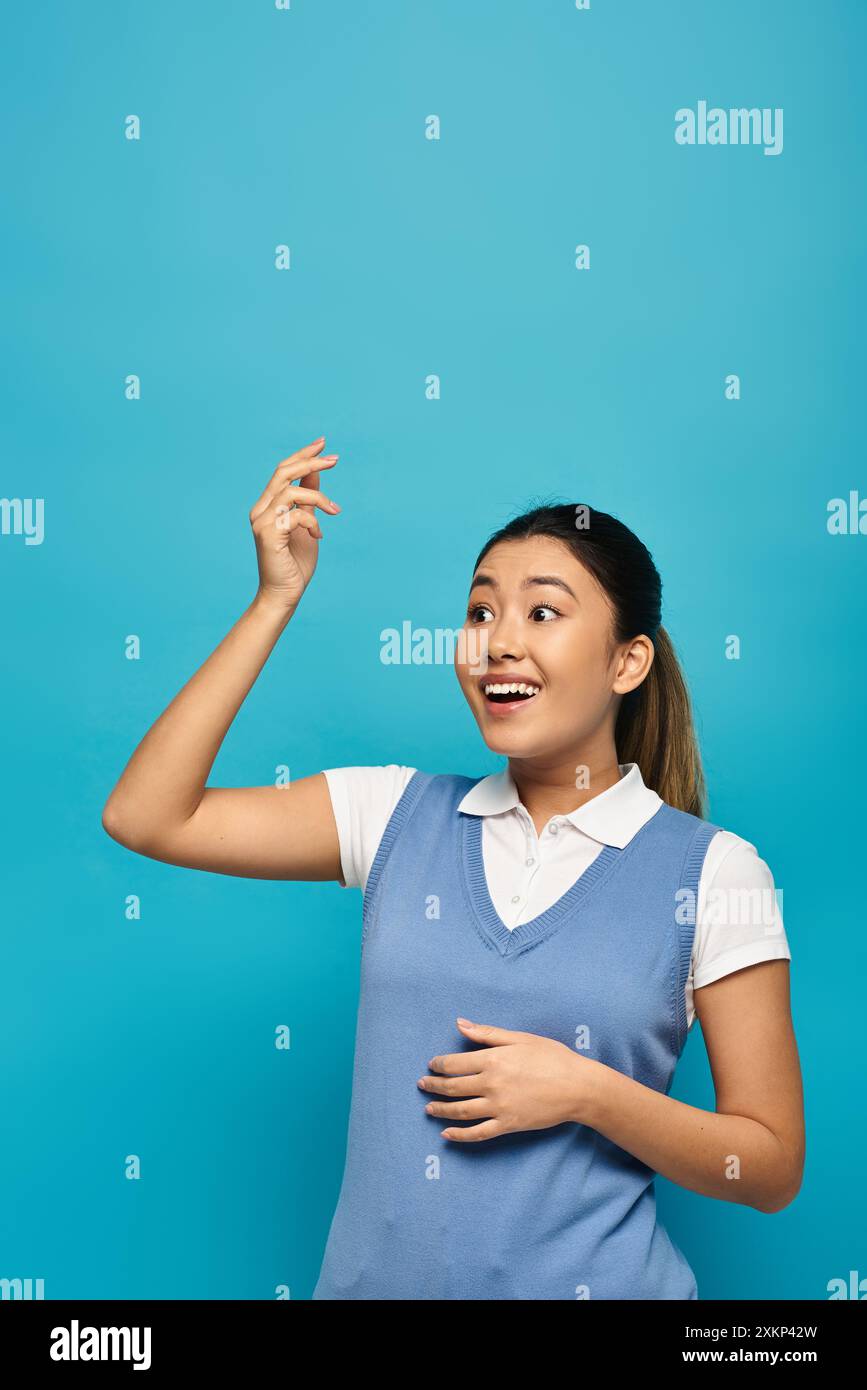 A young Asian woman, dressed in smart casual attire, smiles brightly ...