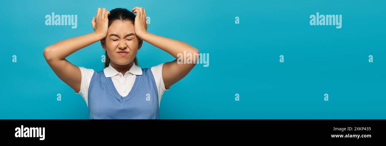 A frustrated young Asian woman in smart casual wear poses against a ...