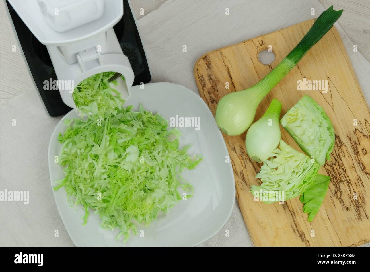 Cabbage and onion in a vegetable cutter on kitchen table. Chopped ...