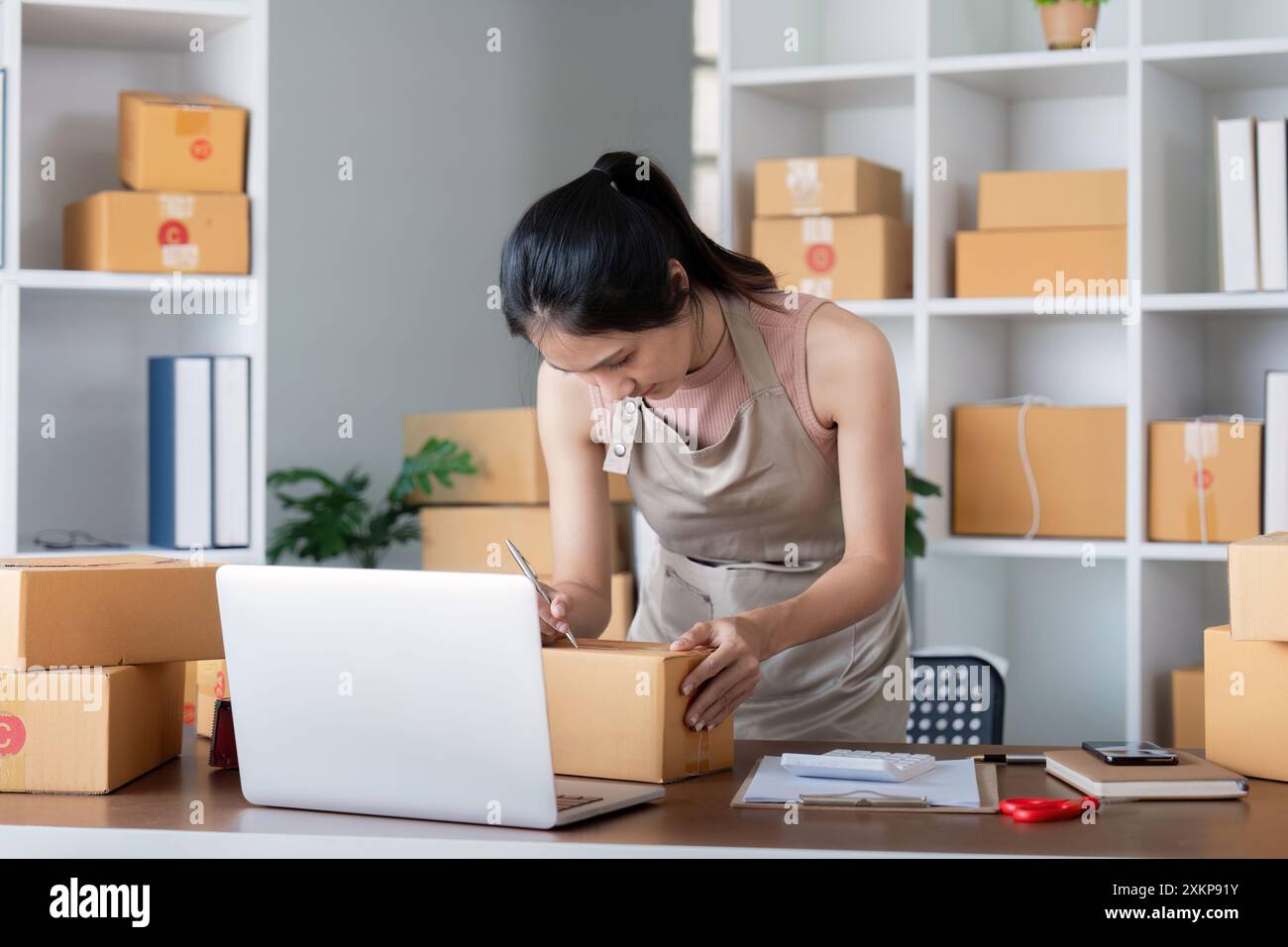 Young Woman Preparing Packages for Shipping in a Home Office with ...
