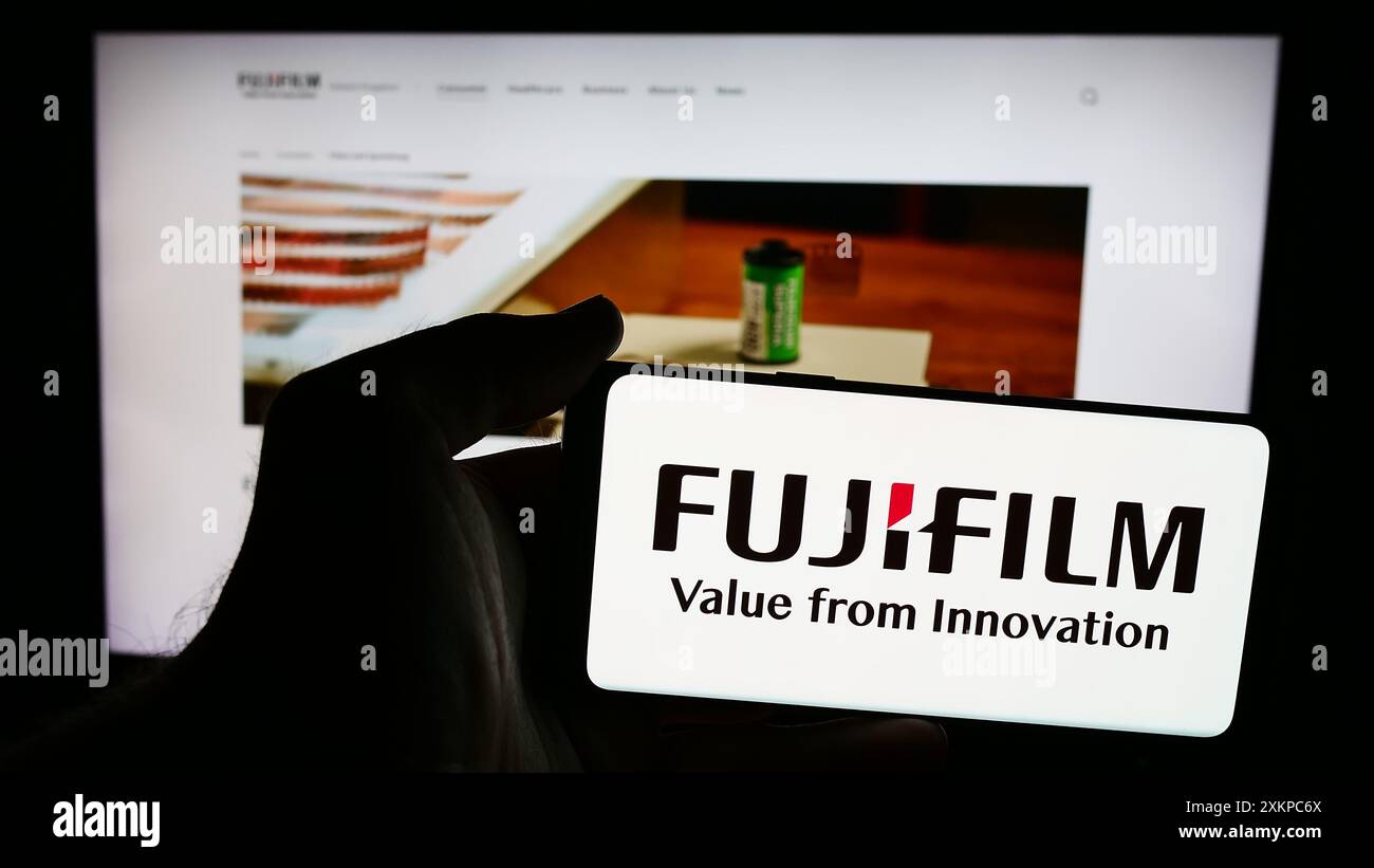 Person holding mobile phone with logo of Japanese company Fujifilm ...