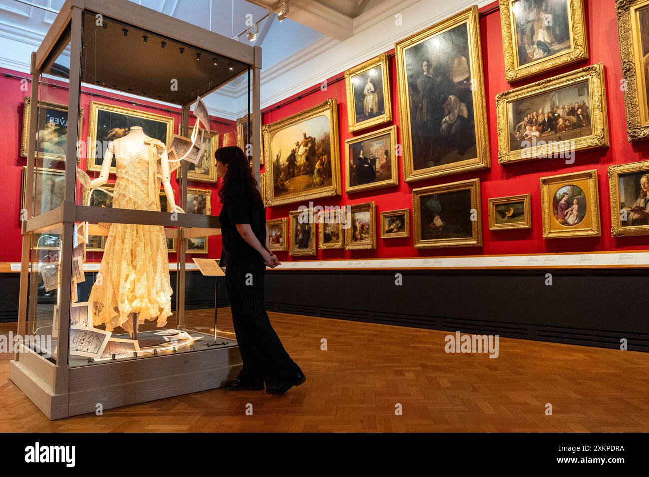 A gallery assistant looks at a costume worn by Taylor Swift in the ...