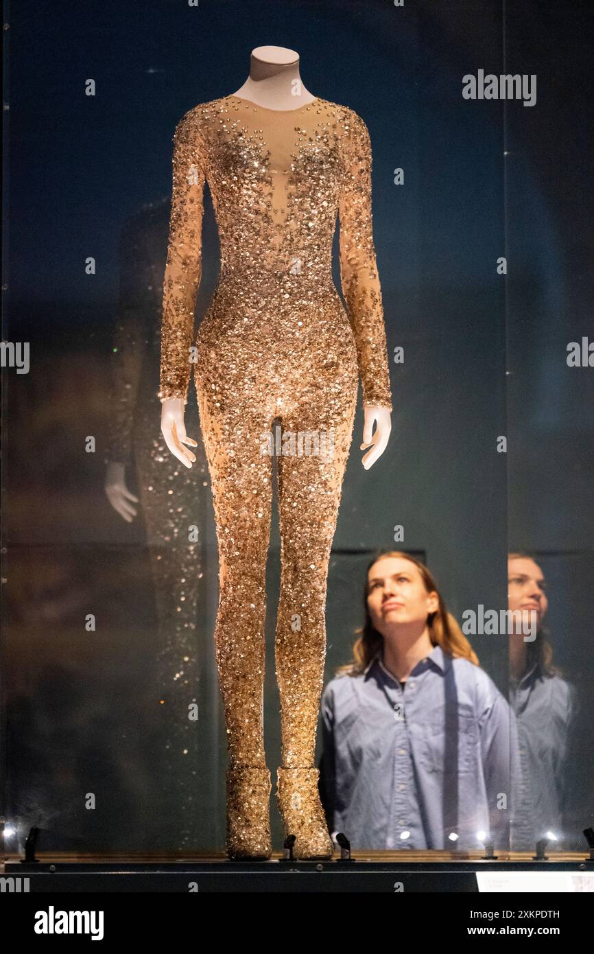 A gallery assistant looks at a costume worn by Taylor Swift on the 1989 ...