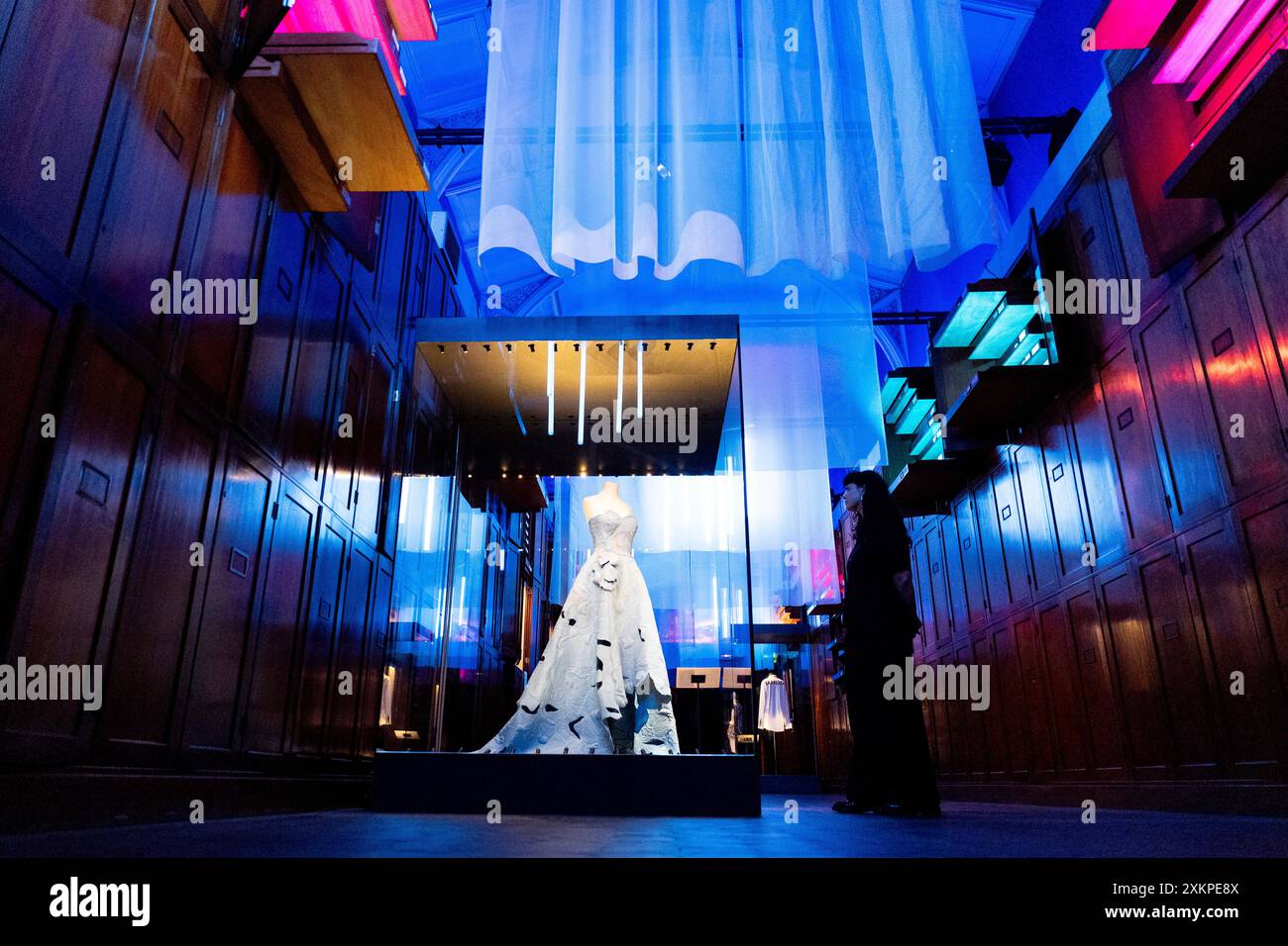 A gallery assistant looks at the gown worn by Taylor Swift for the ...