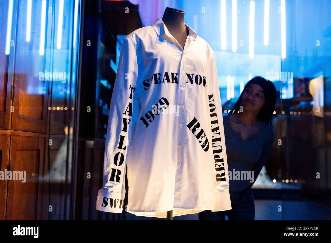 A gallery assistant looks at the dress worn by Taylor Swift at the ...