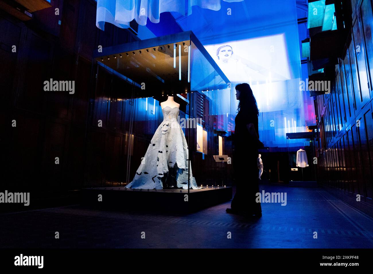 A gallery assistant looks at the gown worn by Taylor Swift for the ...