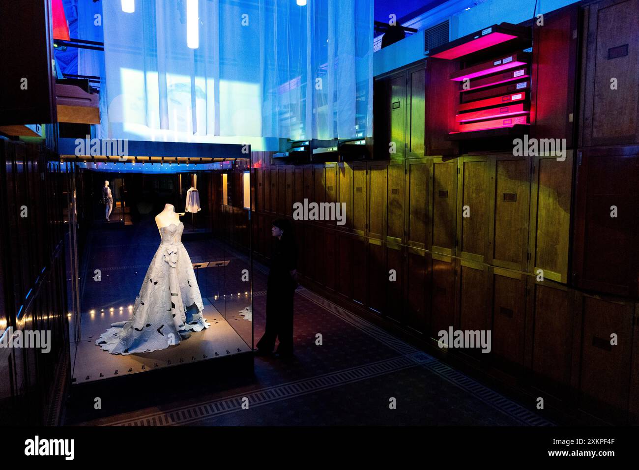 A gallery assistant looks at the gown worn by Taylor Swift for the ...