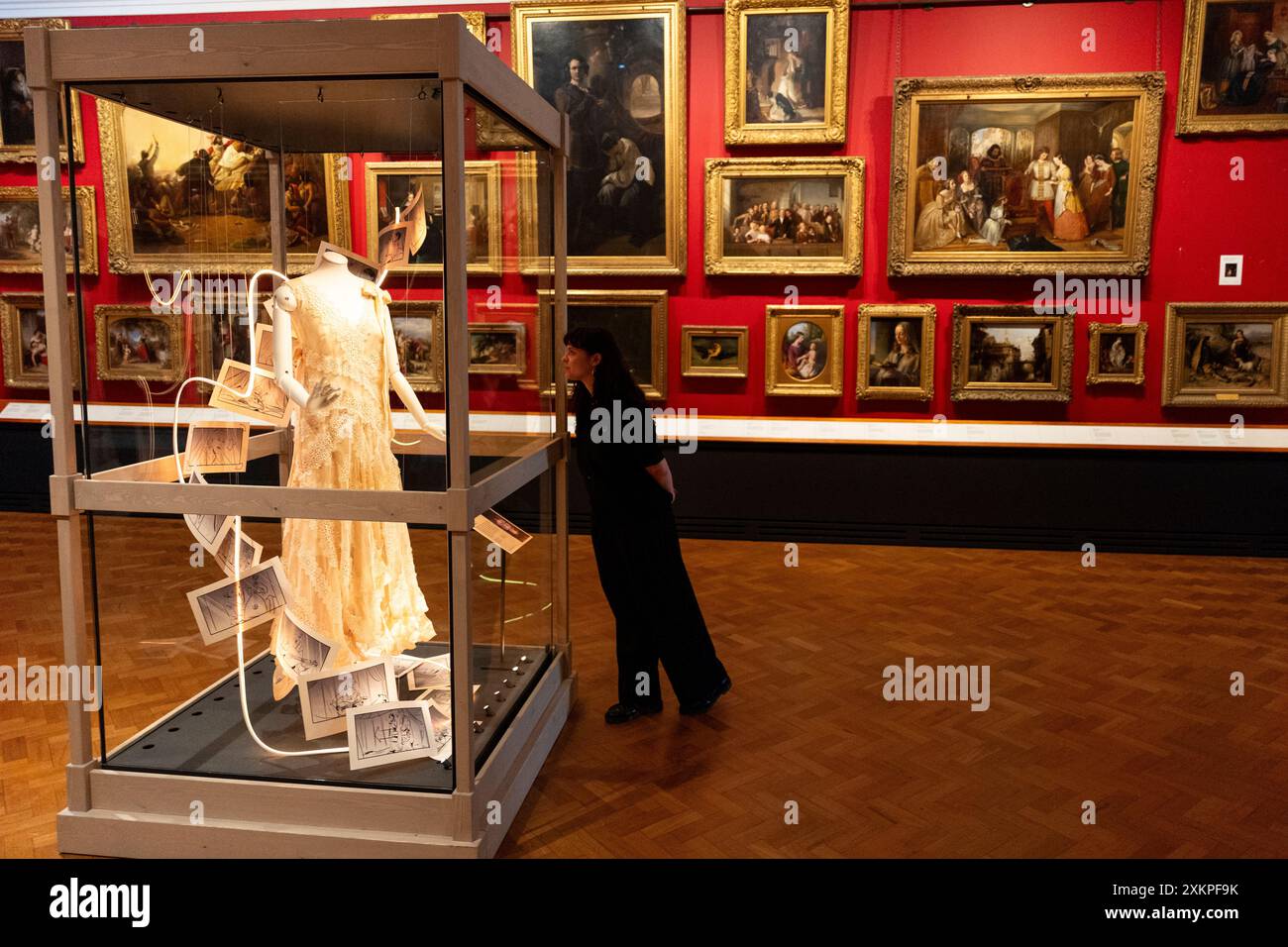 A gallery assistant looks at a costume worn by Taylor Swift in the ...