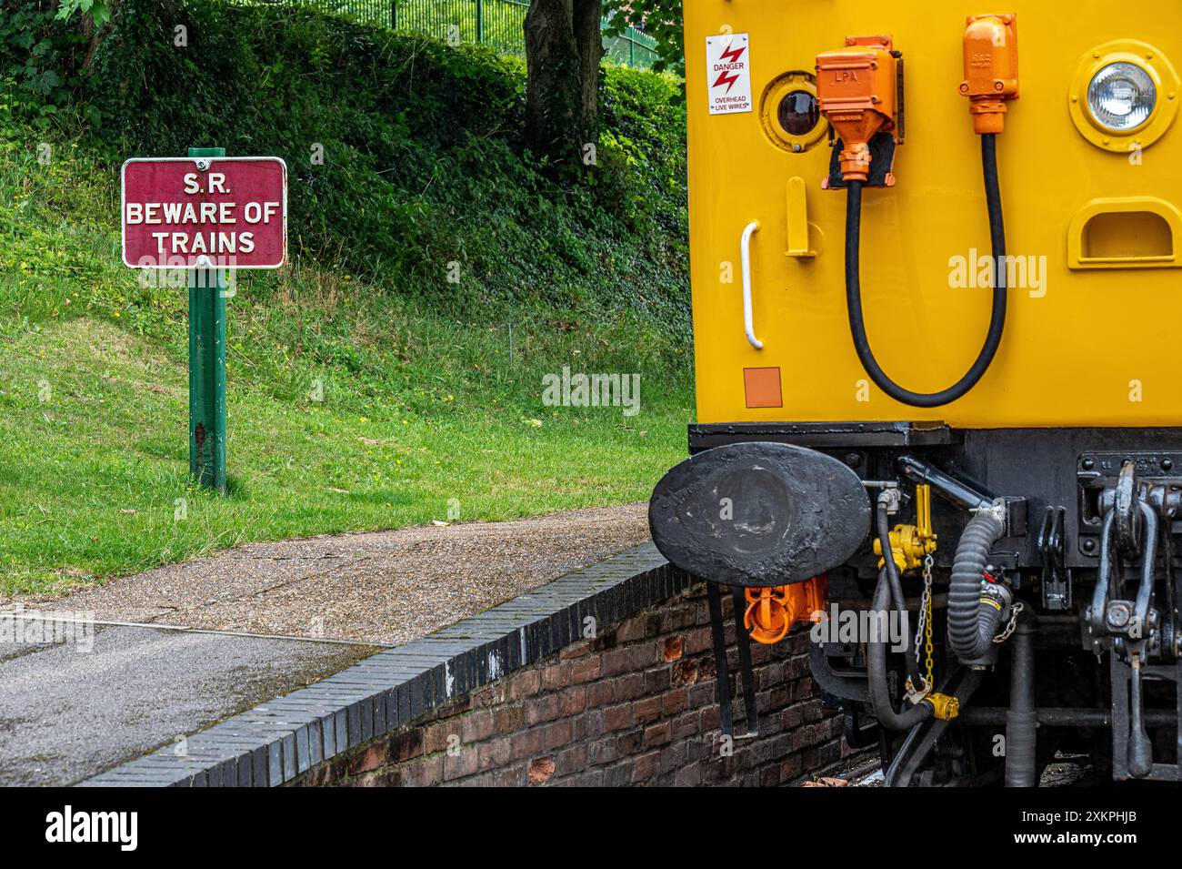 A beware of trains sign along side a stationary diesel train at the ...
