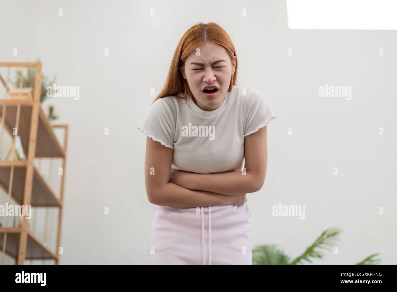 Young Woman Experiencing Stomachache, Holding Her Abdomen in Pain ...