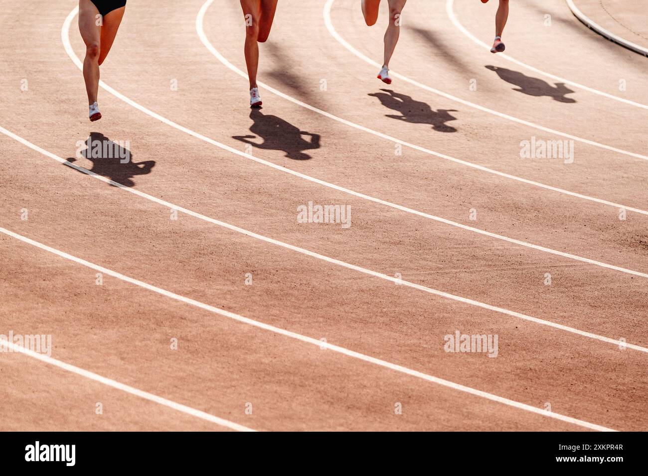 beginning 800-meter race, women legs, shadows on red track stadium ...