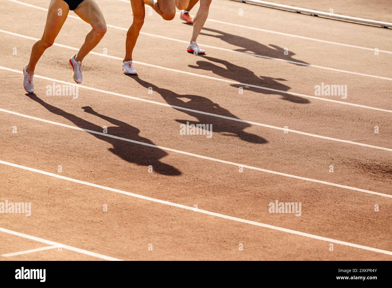 women legs and shadows on red track stadium, middle distance running ...