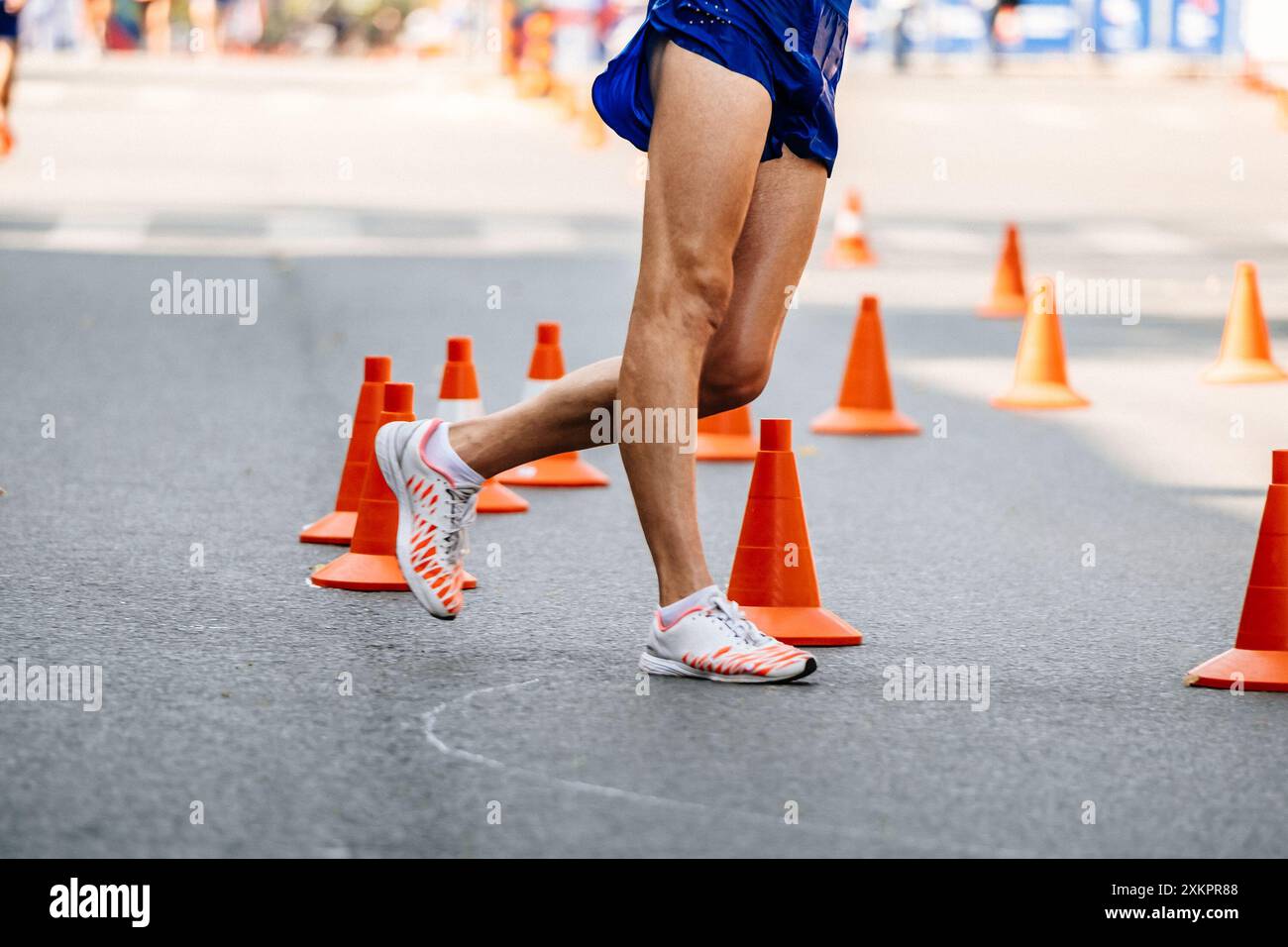 racewalking track, athlete legs, makes a turn around red safety cones ...