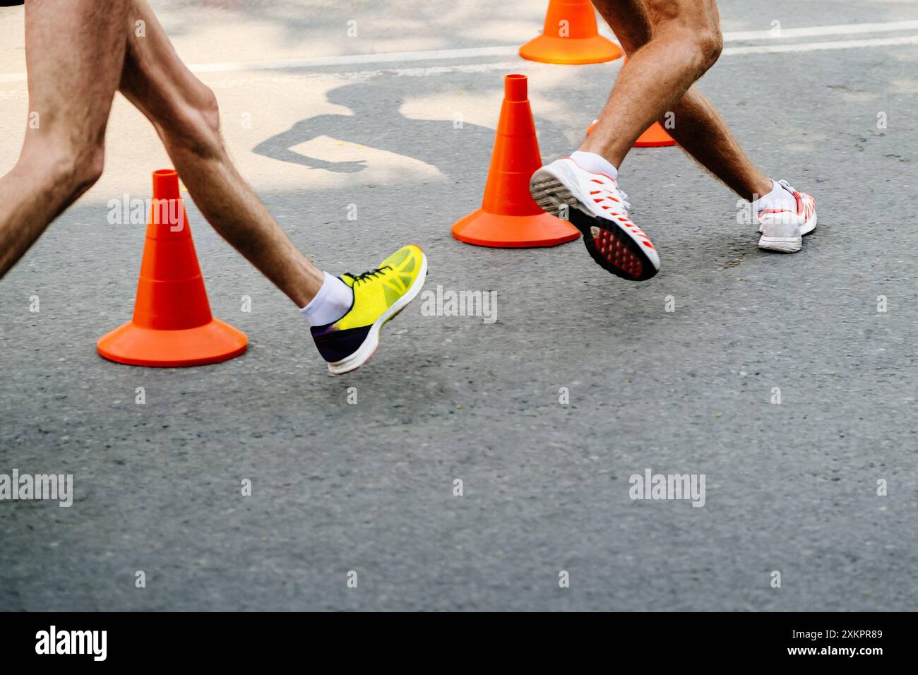 racewalking track, two athlete makes a turn around red safety cones ...