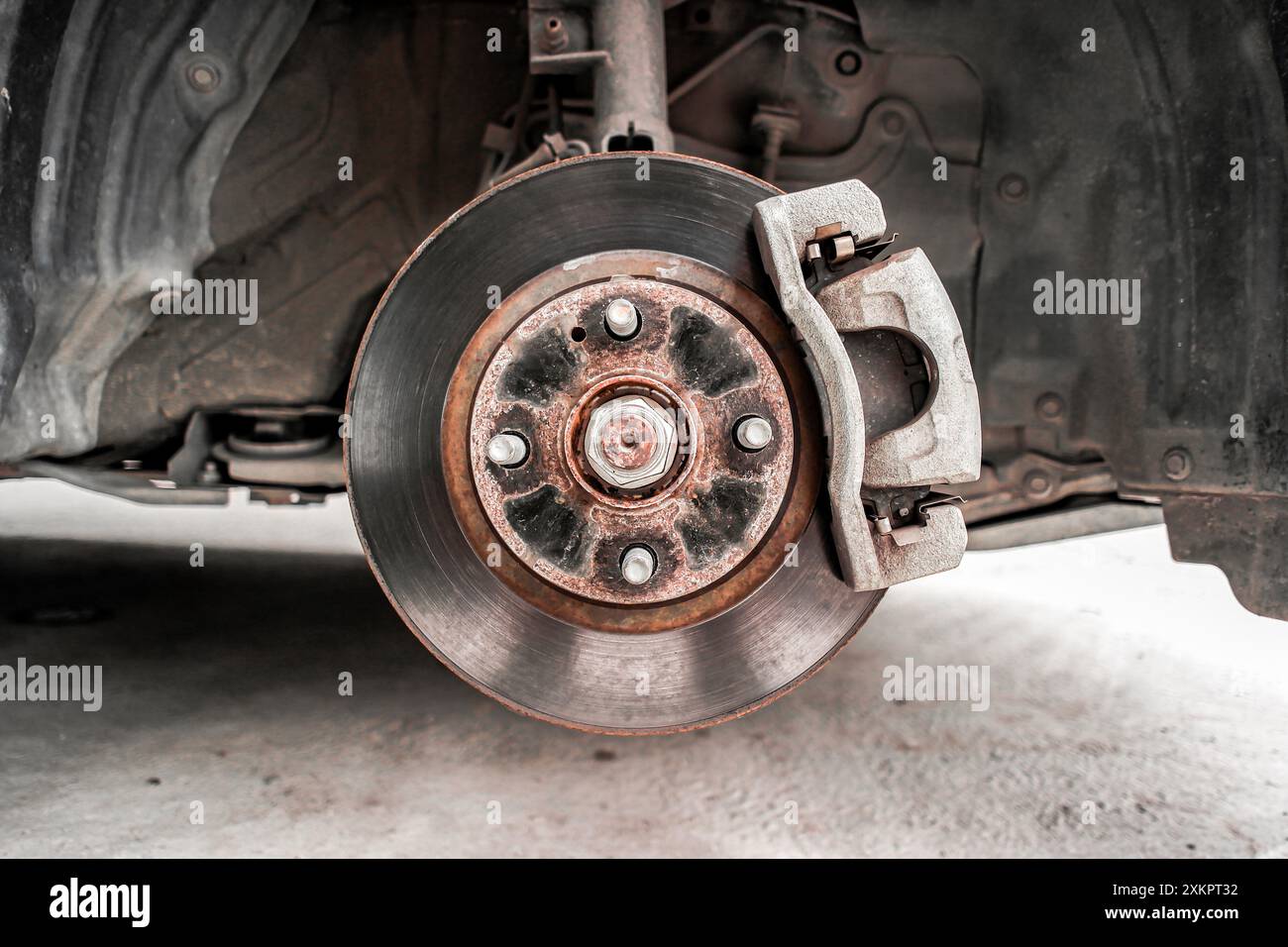Old brake rotor and caliper with brake pad in a suspension of car ...