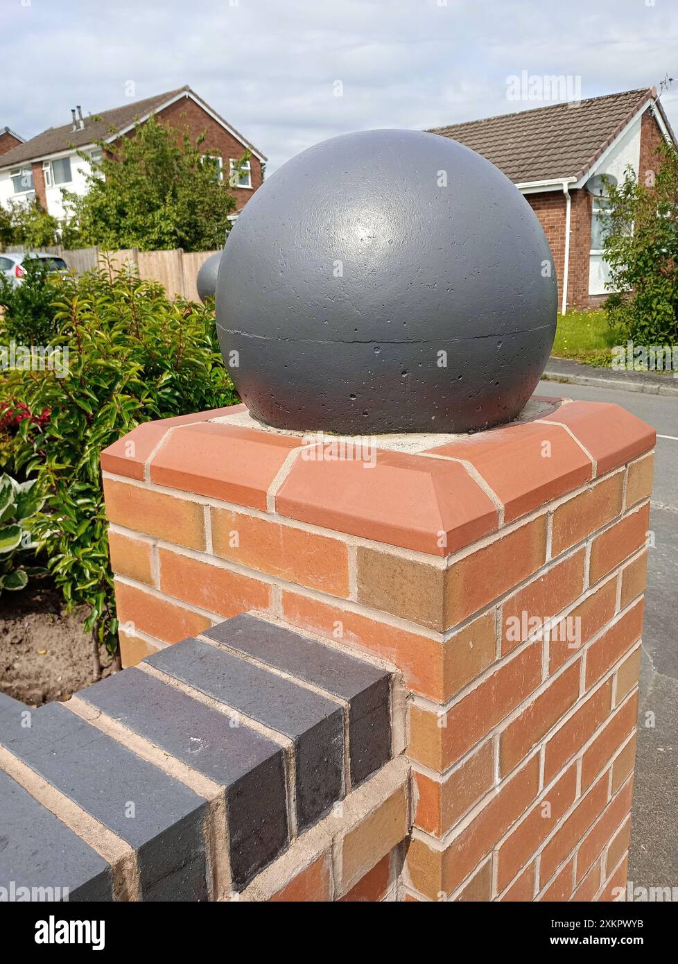 Brick column with coping stones and large grey decorative sphere on top ...