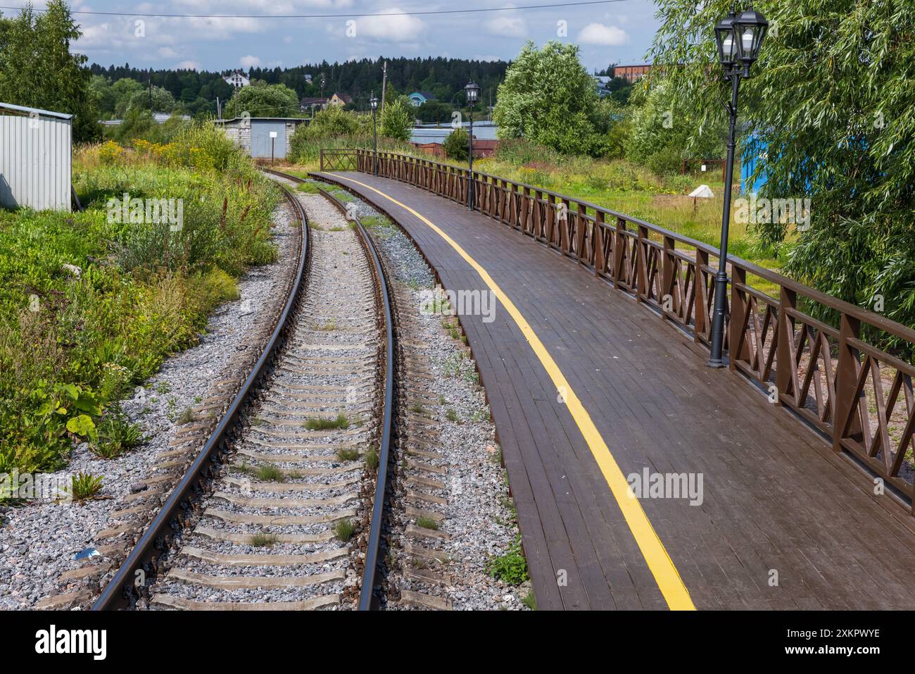 An empty railway track turning left along a station platform with ...