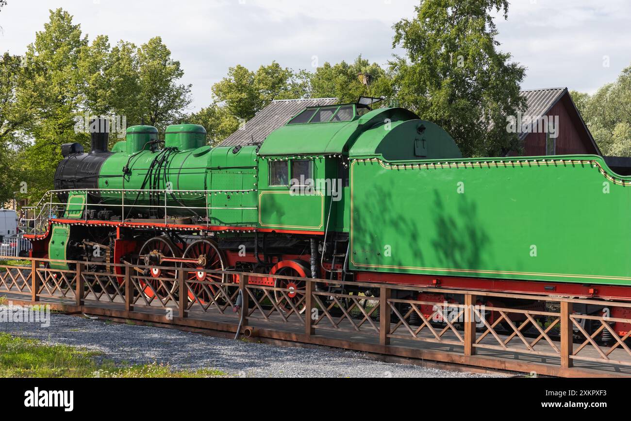 Vintage green steam locomotive with red and black details is near an ...