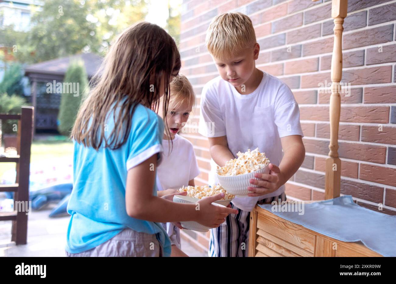 Small children are eating popcorn in the backyard of the house. Cute ...