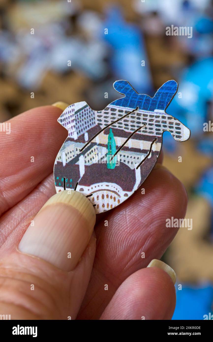 Hand holding Wentworth whimsy piece jigsaw puzzle piece above box of ...