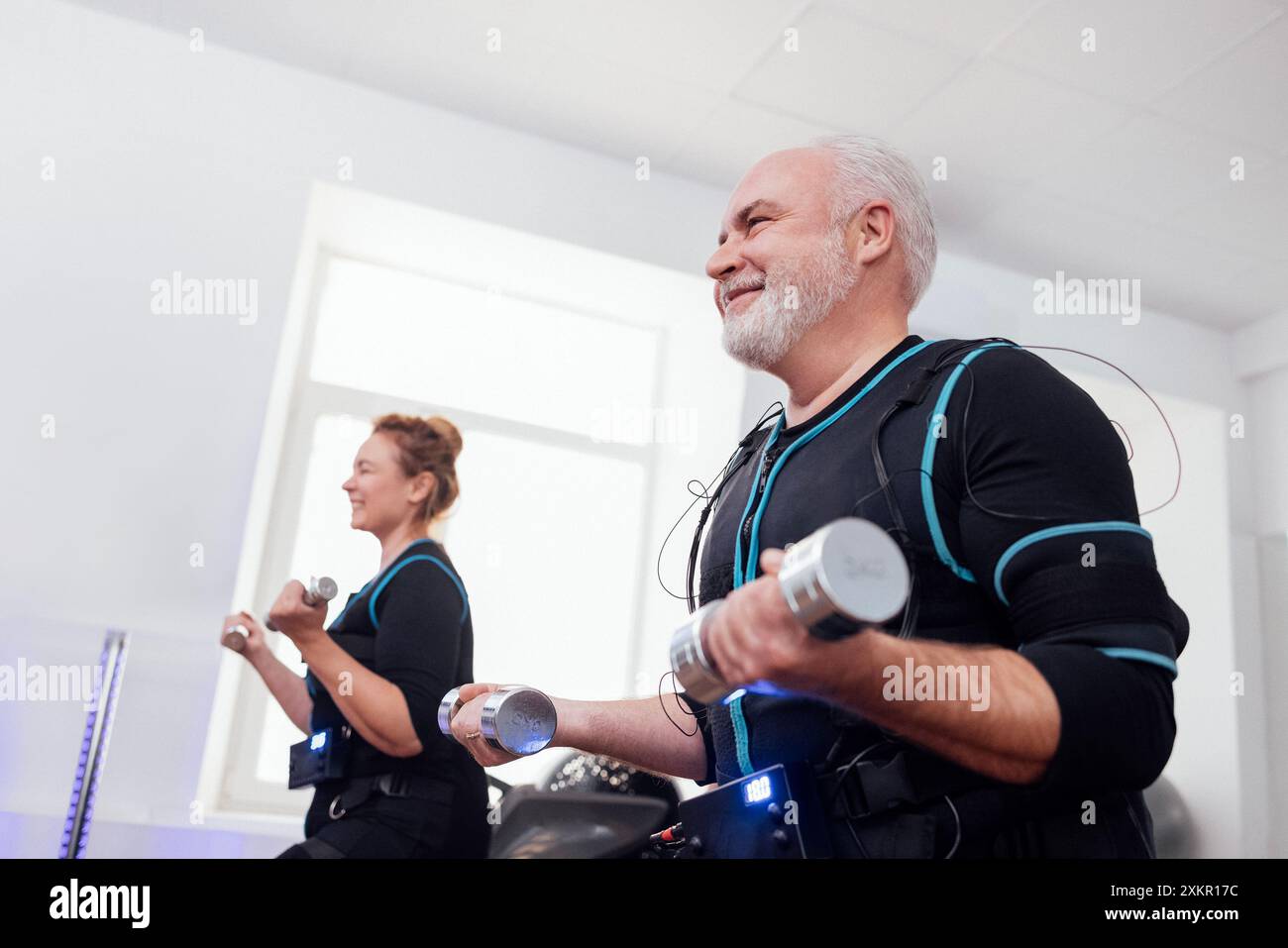 Older smiling couple in ems suits doing electrical muscle stimulation ...